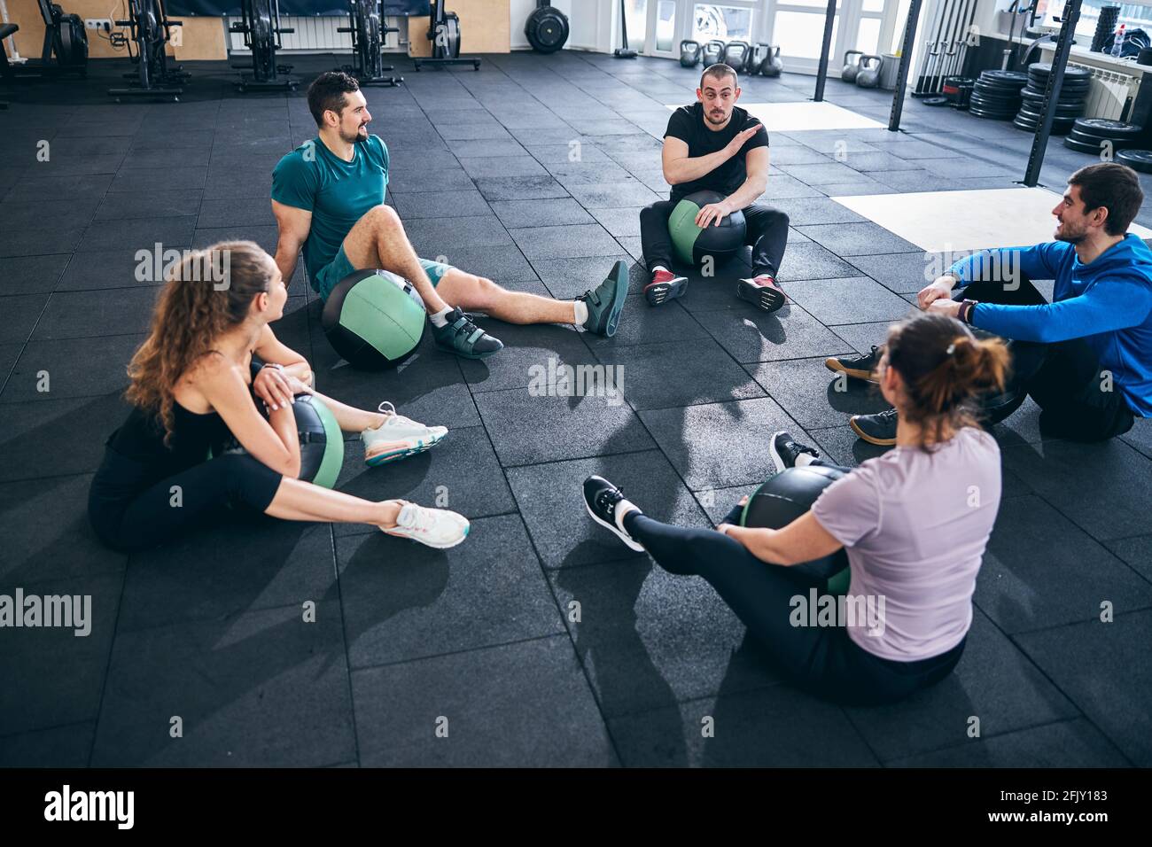 Four athletes listening to their fitness coach Stock Photo - Alamy