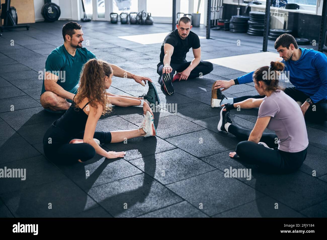 Athletes doing the seated forward bend on the floor Stock Photo - Alamy