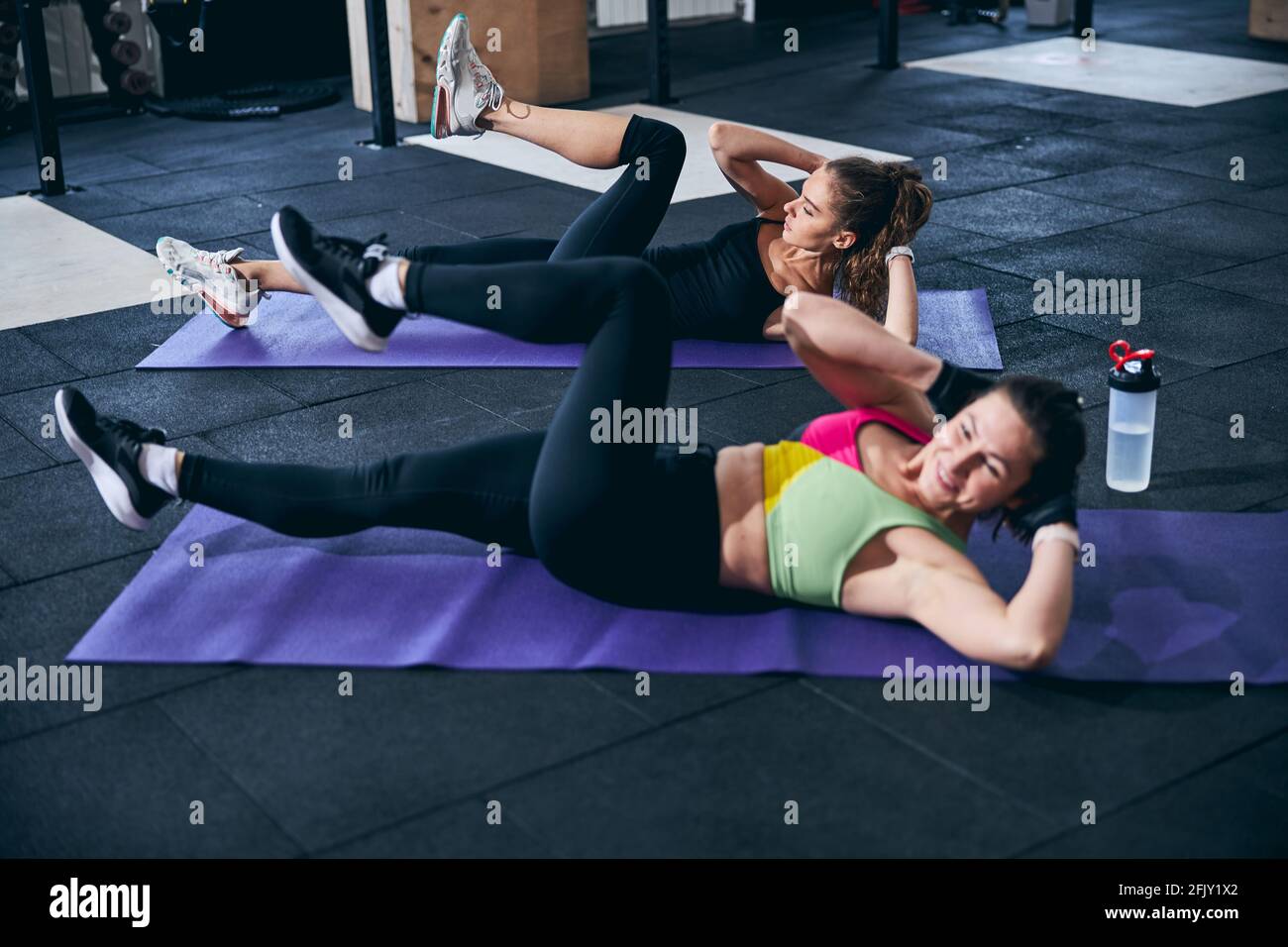 Serious lady and her personal trainer working their abdominal muscles ...