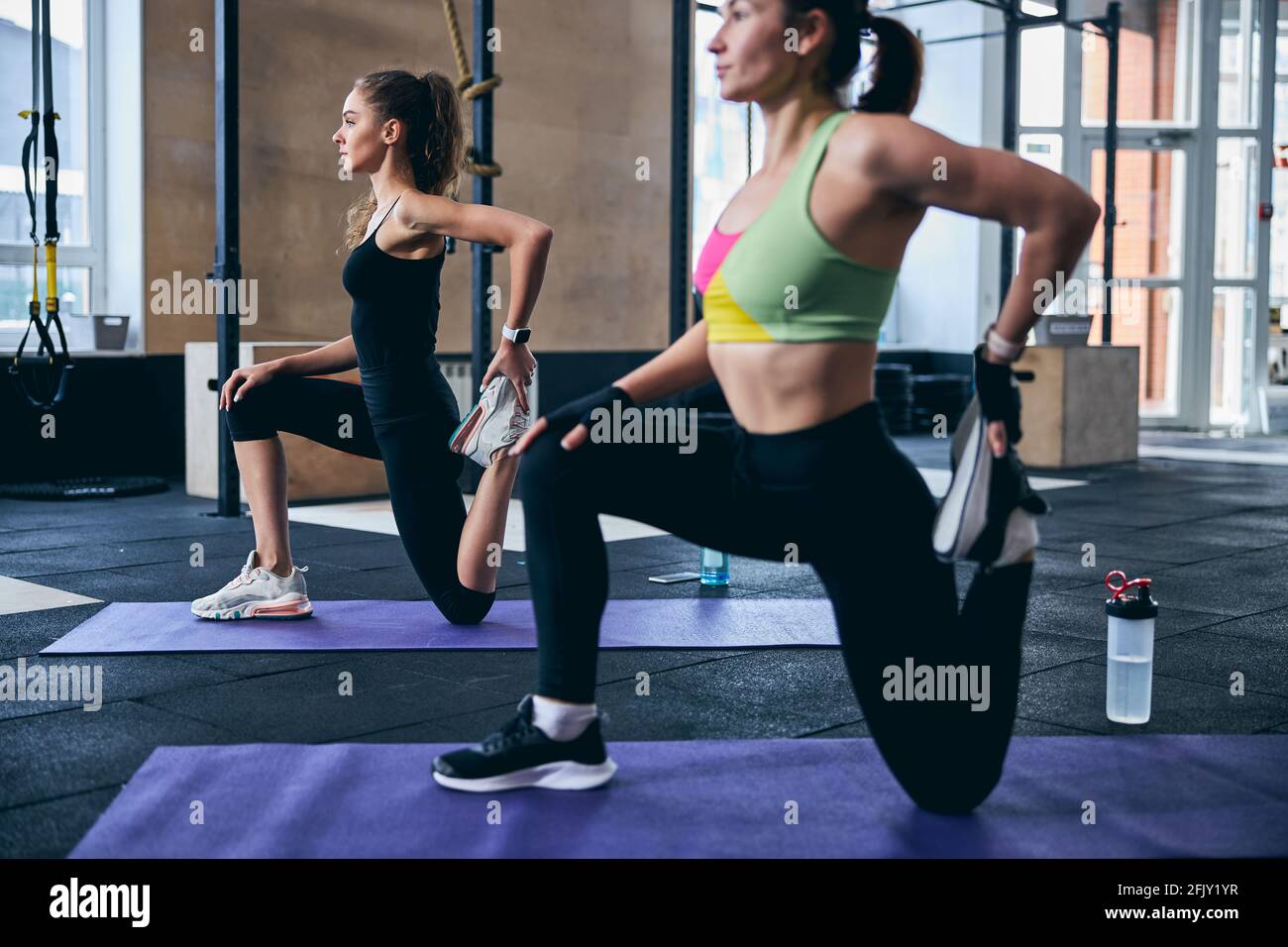 Two fit ladies doing the quad stretches Stock Photo - Alamy