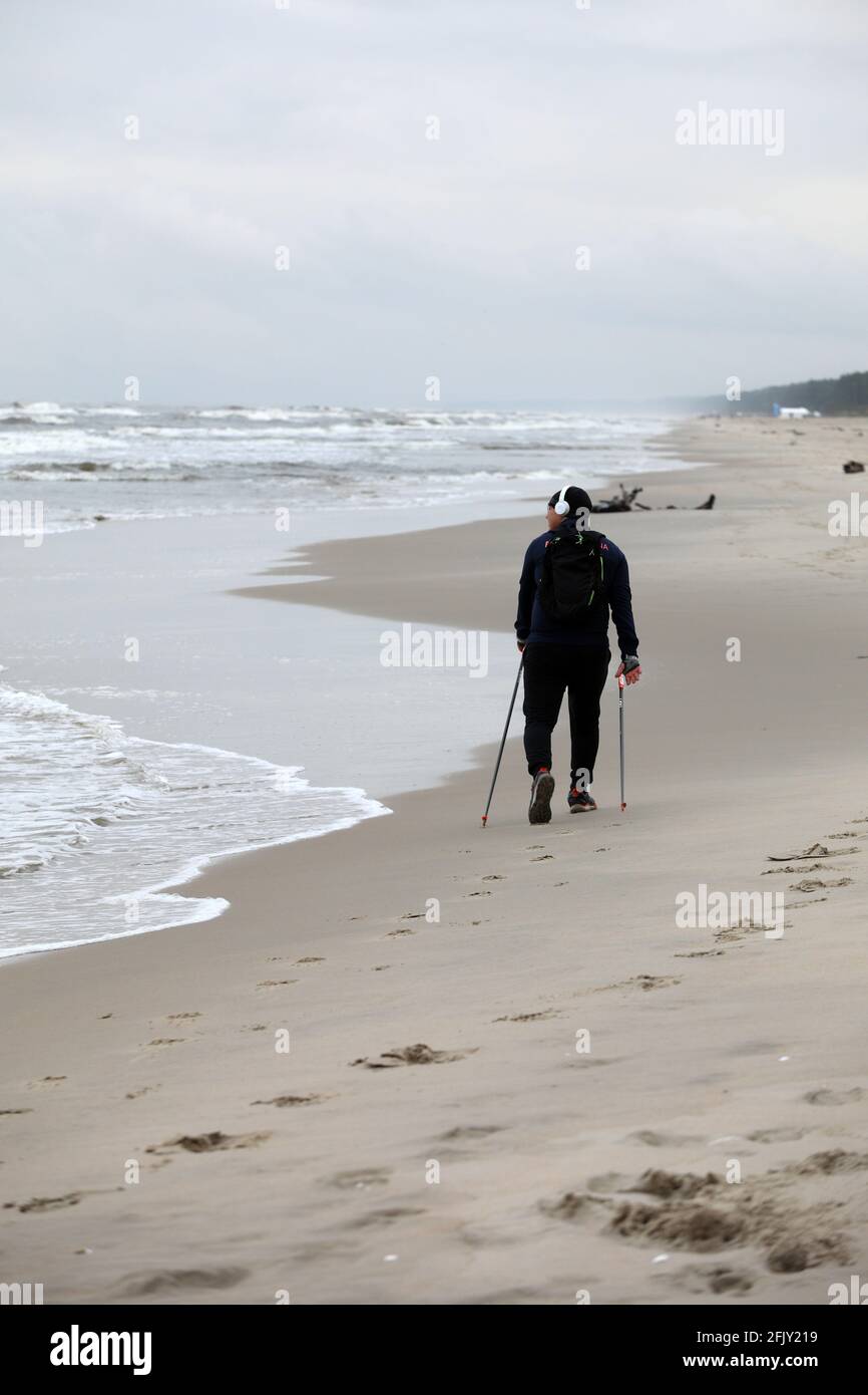 Active and healthy lifestyle. Nordic walking on a sandy beach sea shore ...