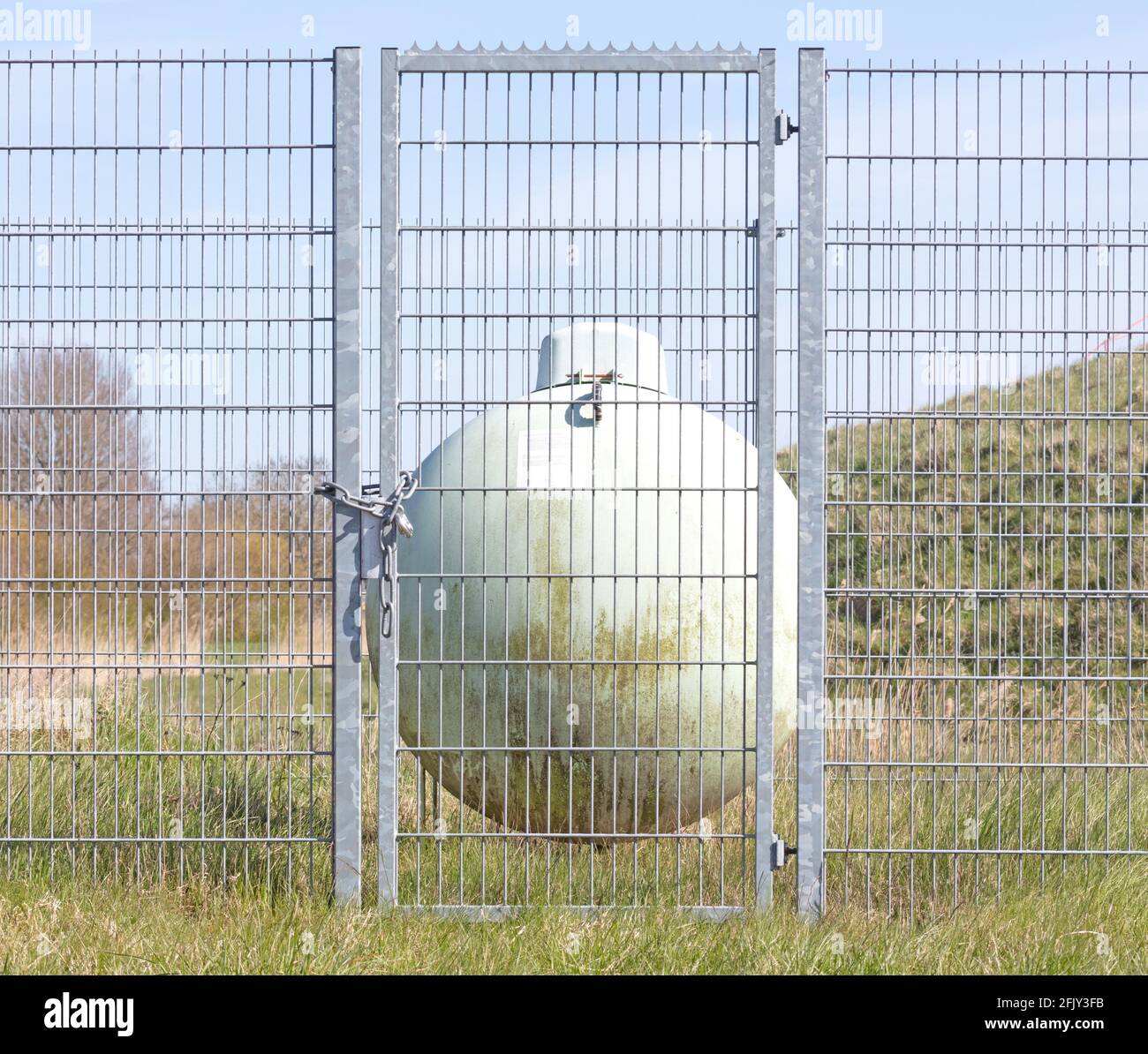Large gas tank behind a metal fence Stock Photo - Alamy