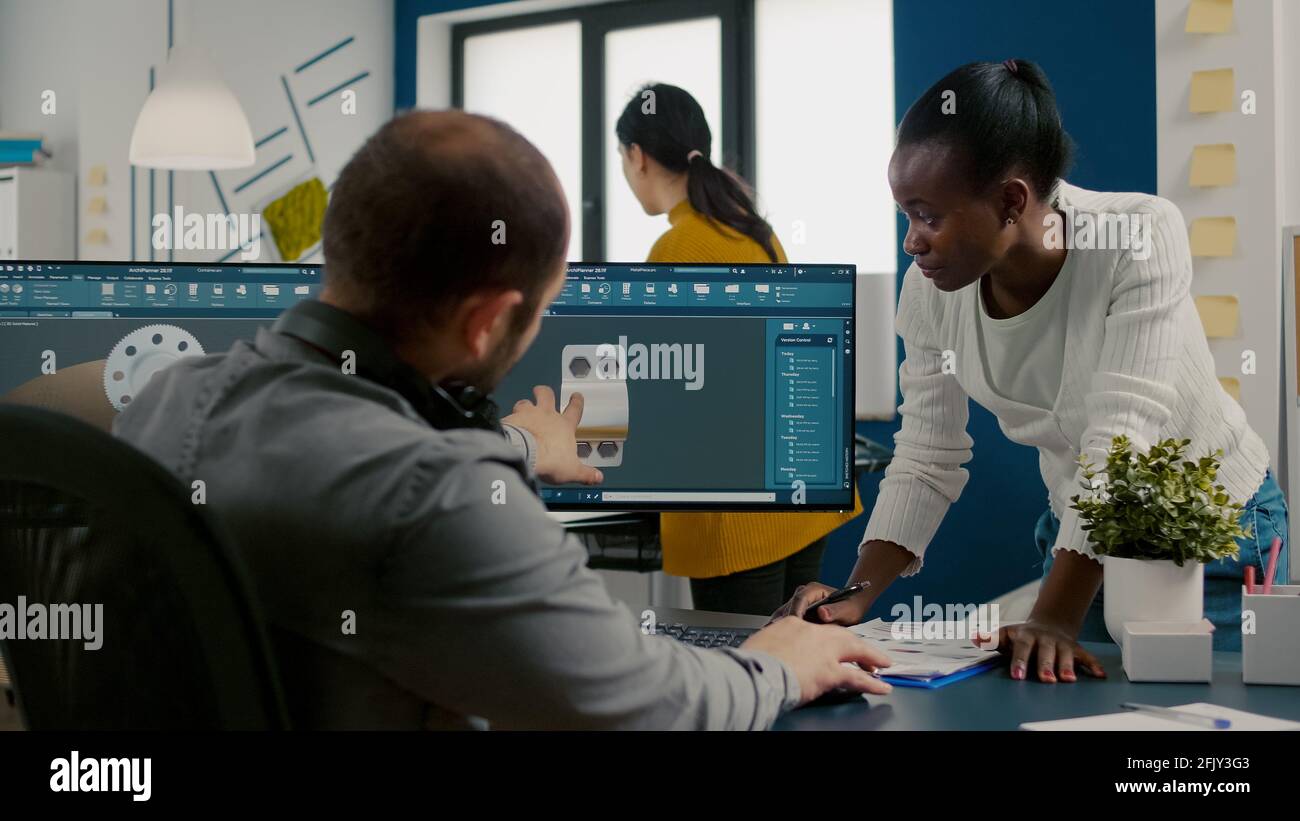 Diverse engineers working on computer at mechanical pieces design ...