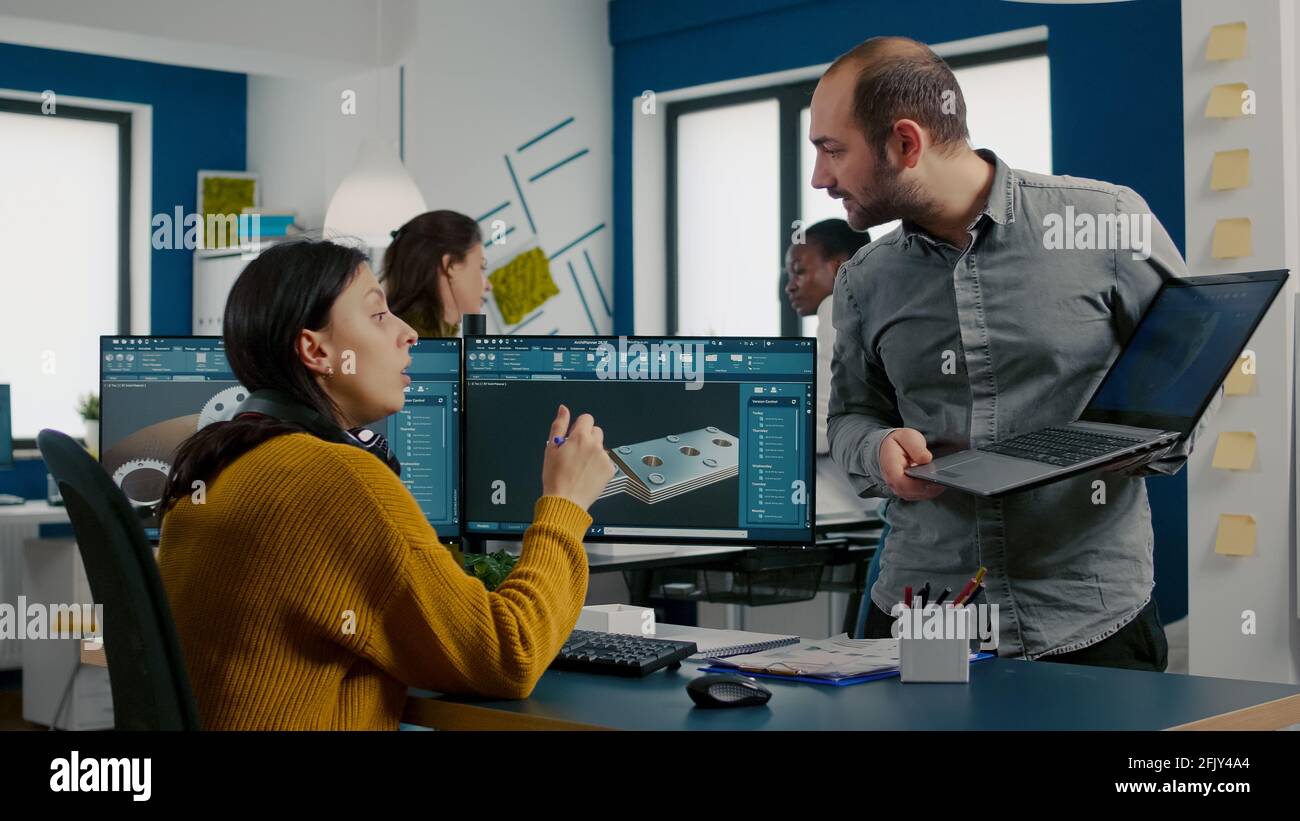 Engineers talking in front on pc and laptop with CAD software ...