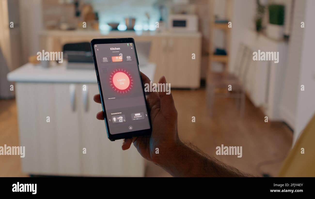Person sitting in house with automation light system holding smartphone ...