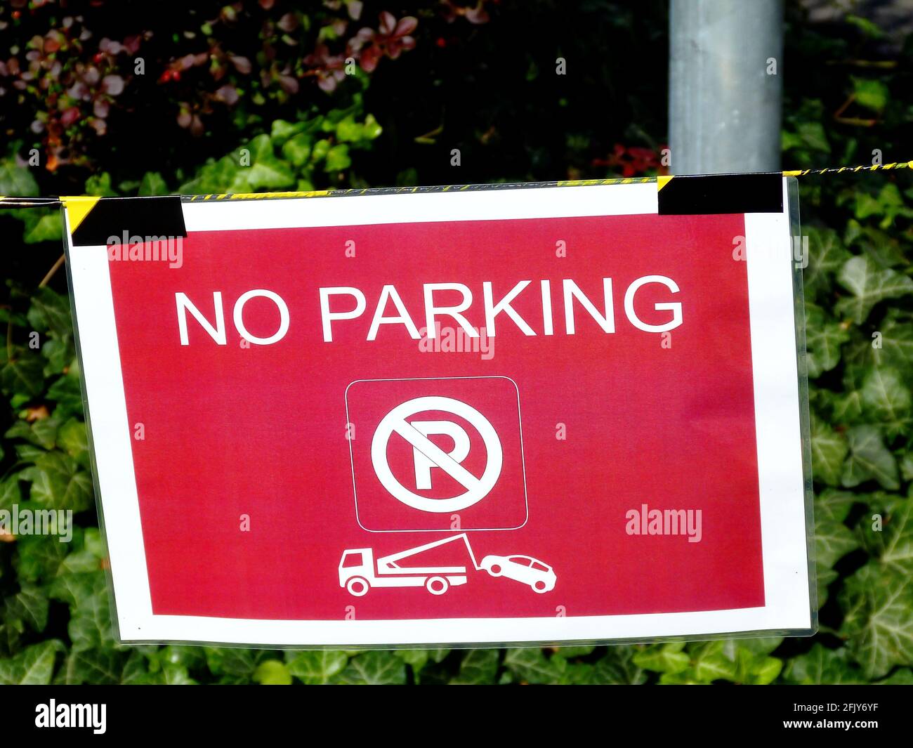 No parking traffic sign in red and white suspended from street wire ...
