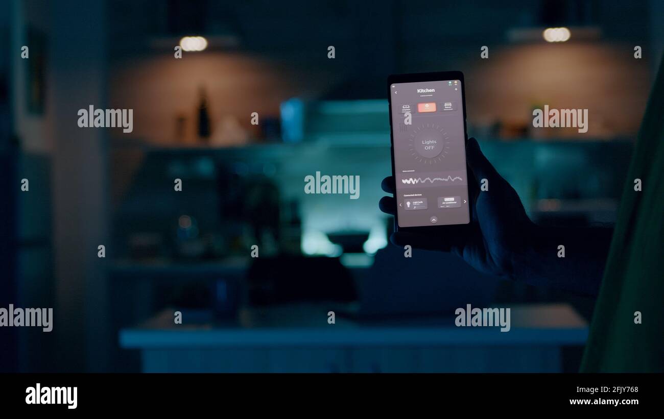 Person holding mobile phone with high tech application in smart house ...