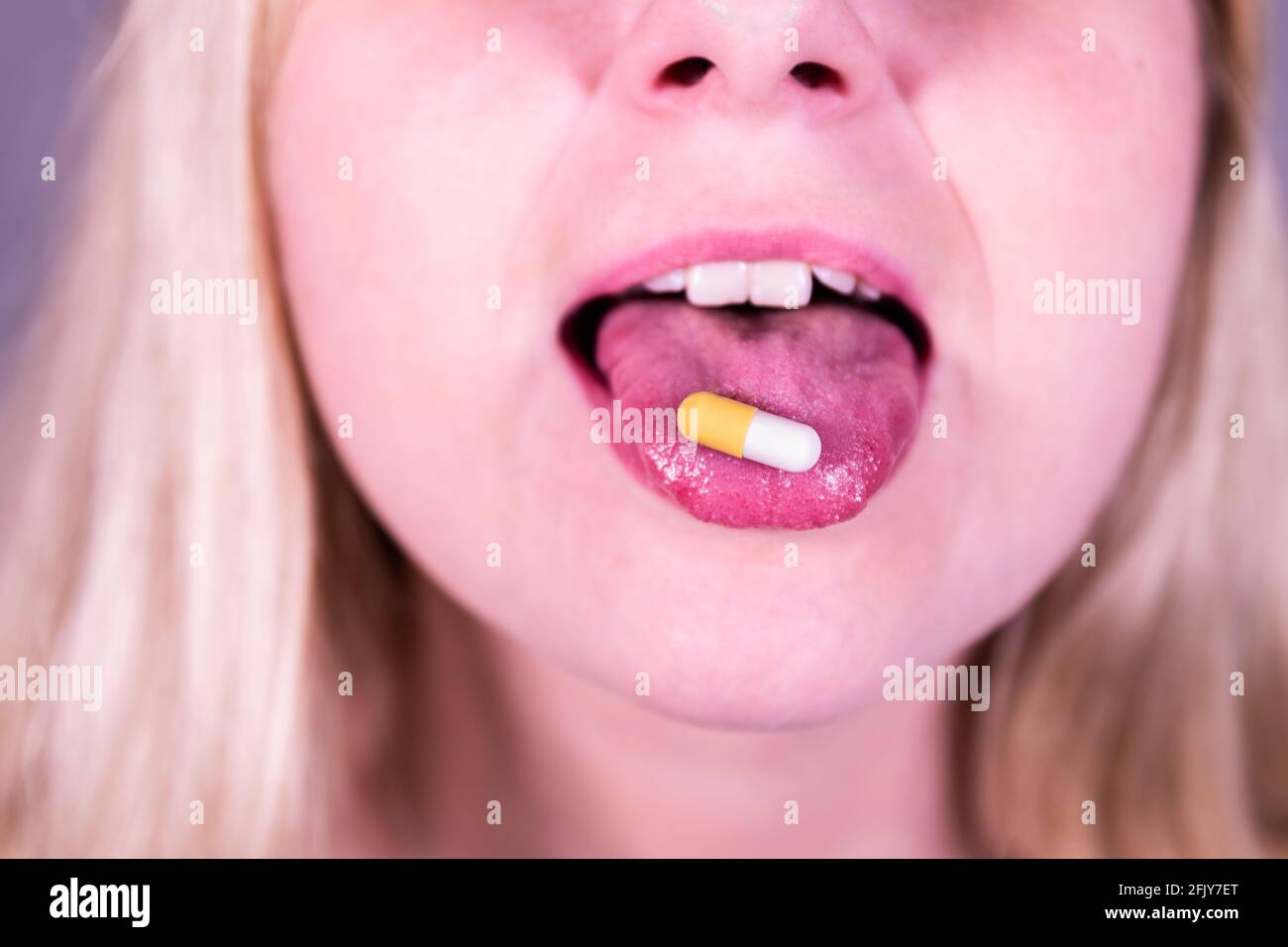 Blonde girl taking a pill - too much medicine Stock Photo - Alamy