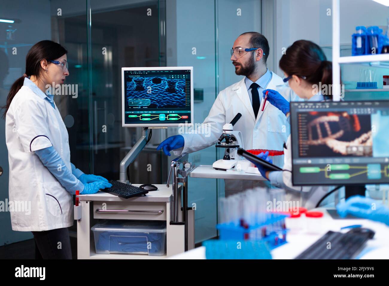 Research scientists working on monitor analyzing virus with chemistry ...