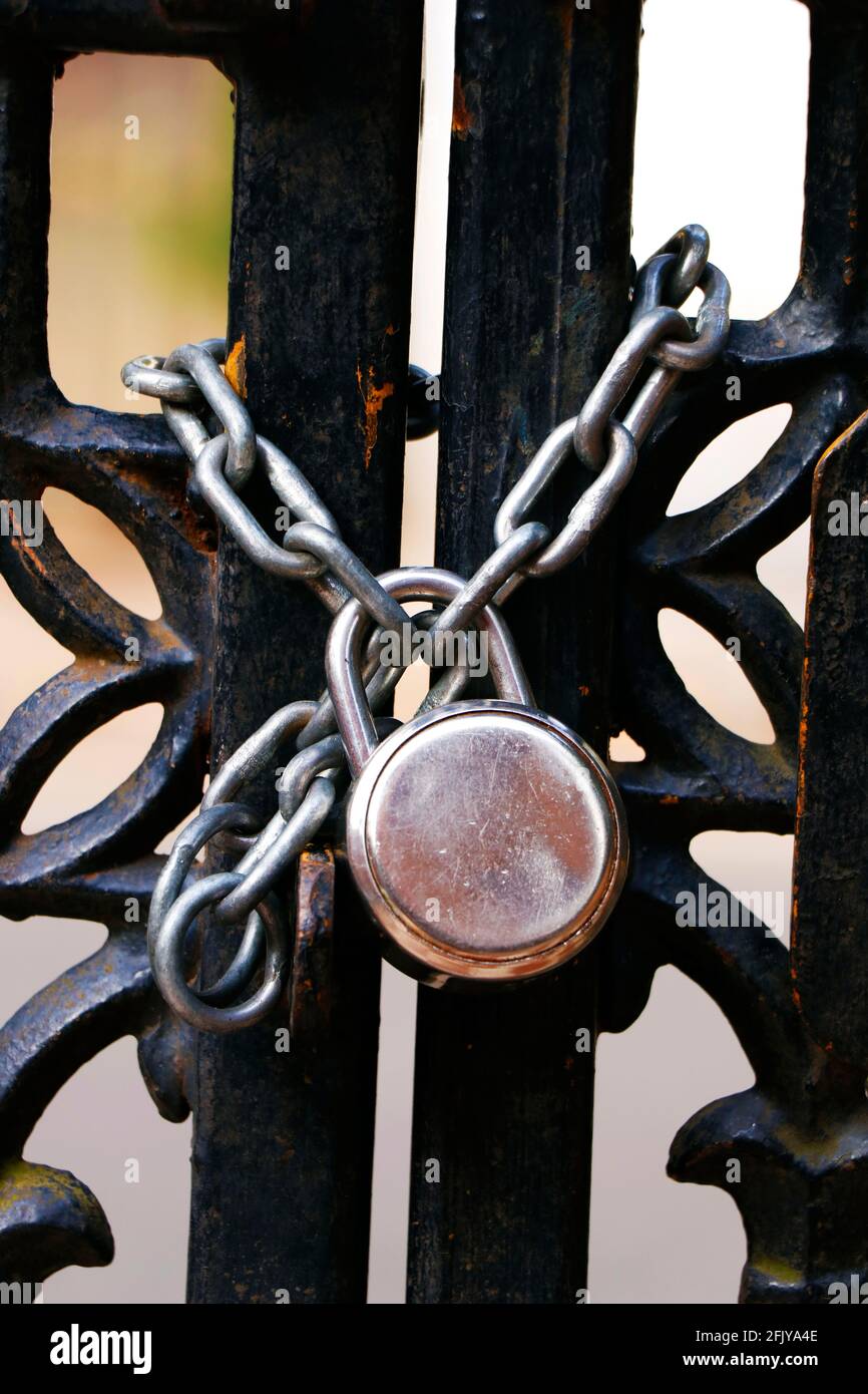 padlock and strong steel chain wrapped around the metal entrance gate ...