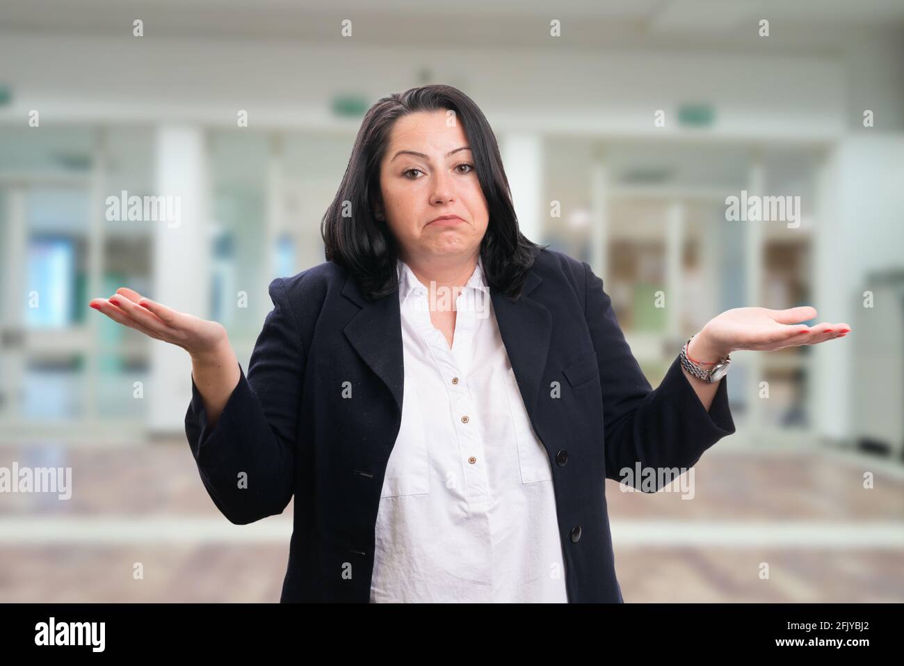 Confused businesswoman wearing smart casual office suit making shrug ...