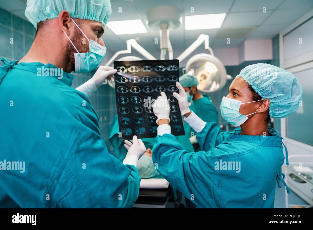 Team of surgeon doctors looking at x-ray film before surgery to set up ...