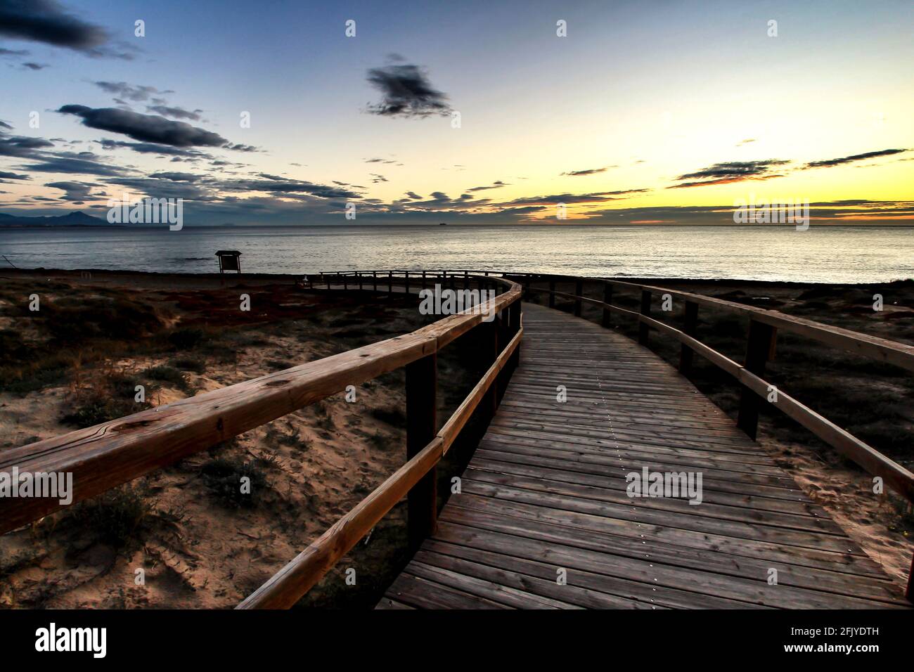 Wooden walkway to Arenales del Sol beach in a beautiful with sunrise ...