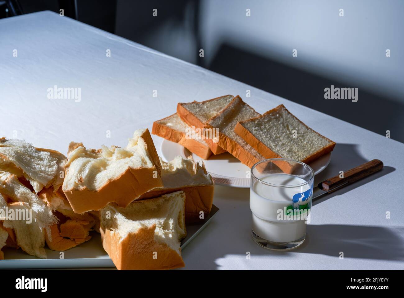 Hand shredded and sliced raw toast bread and milk, breakfast scene ...