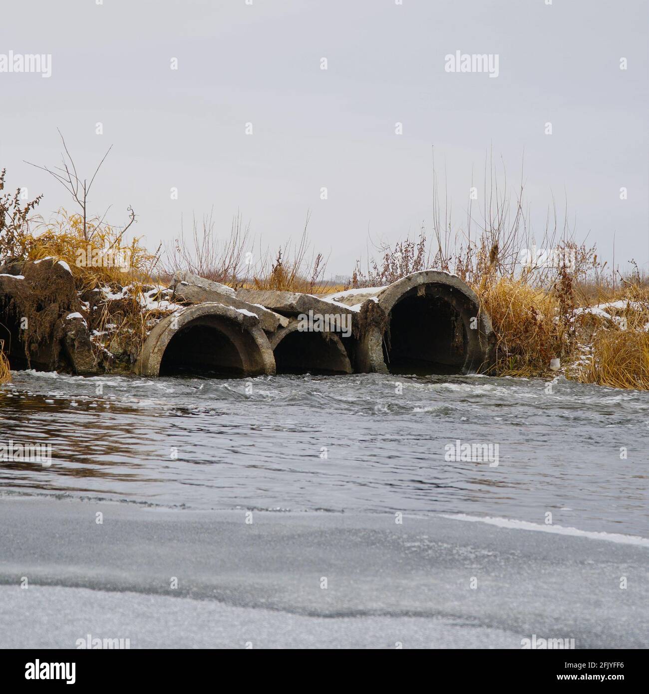 The water on the river flows from large pipes. Dam on the river Stock ...