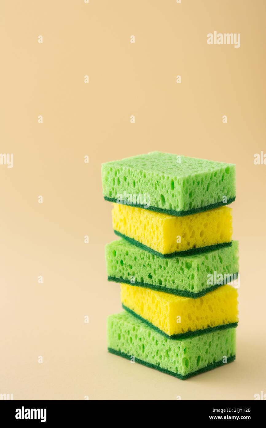 Stack of green and yellow dishwashing sponges on neutral beige ...