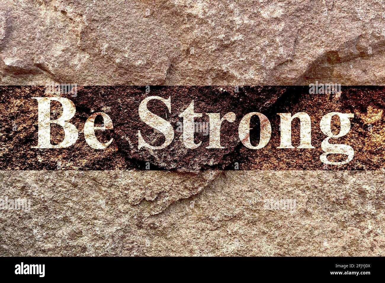 Creative design of bright English text “Be Strong” on the rock wall ...