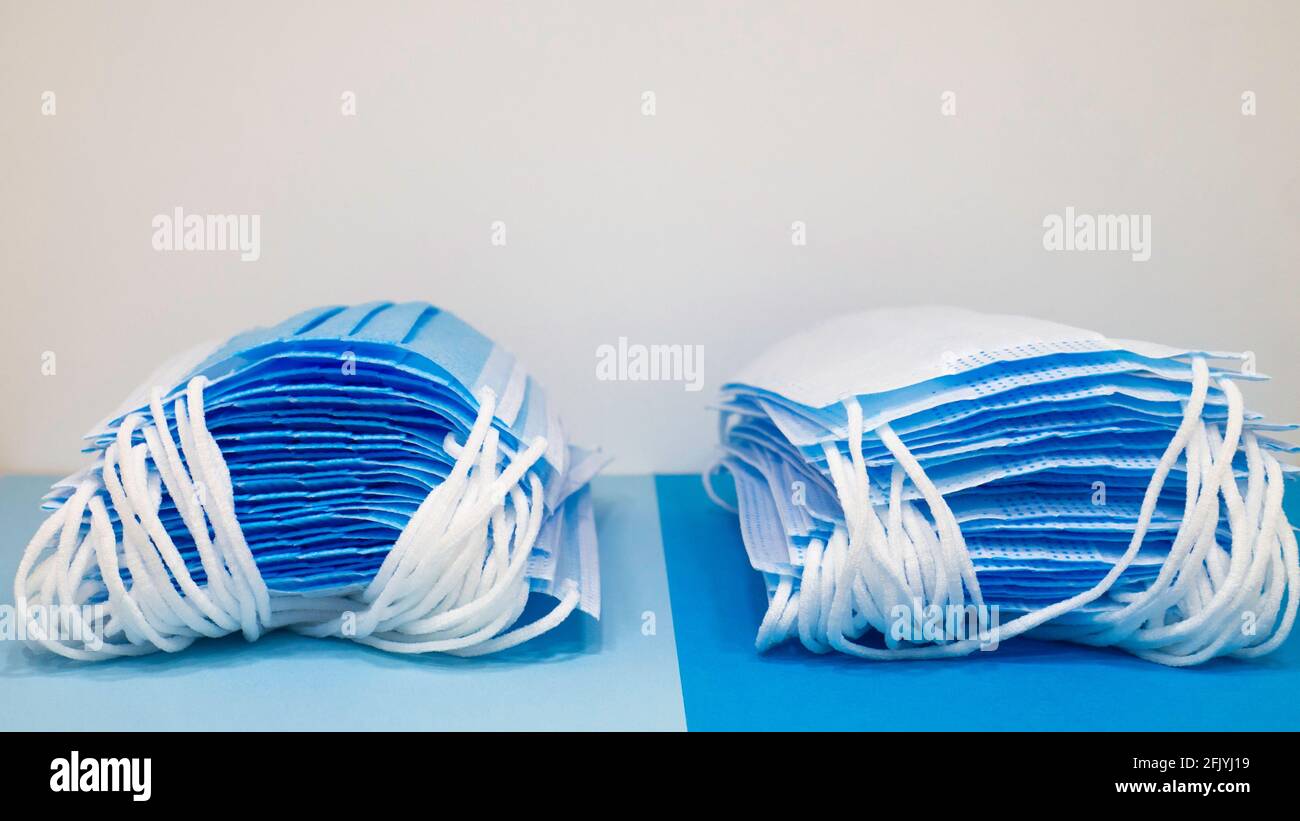 Two stacks of medical masks lying on the blue background. Negative ...