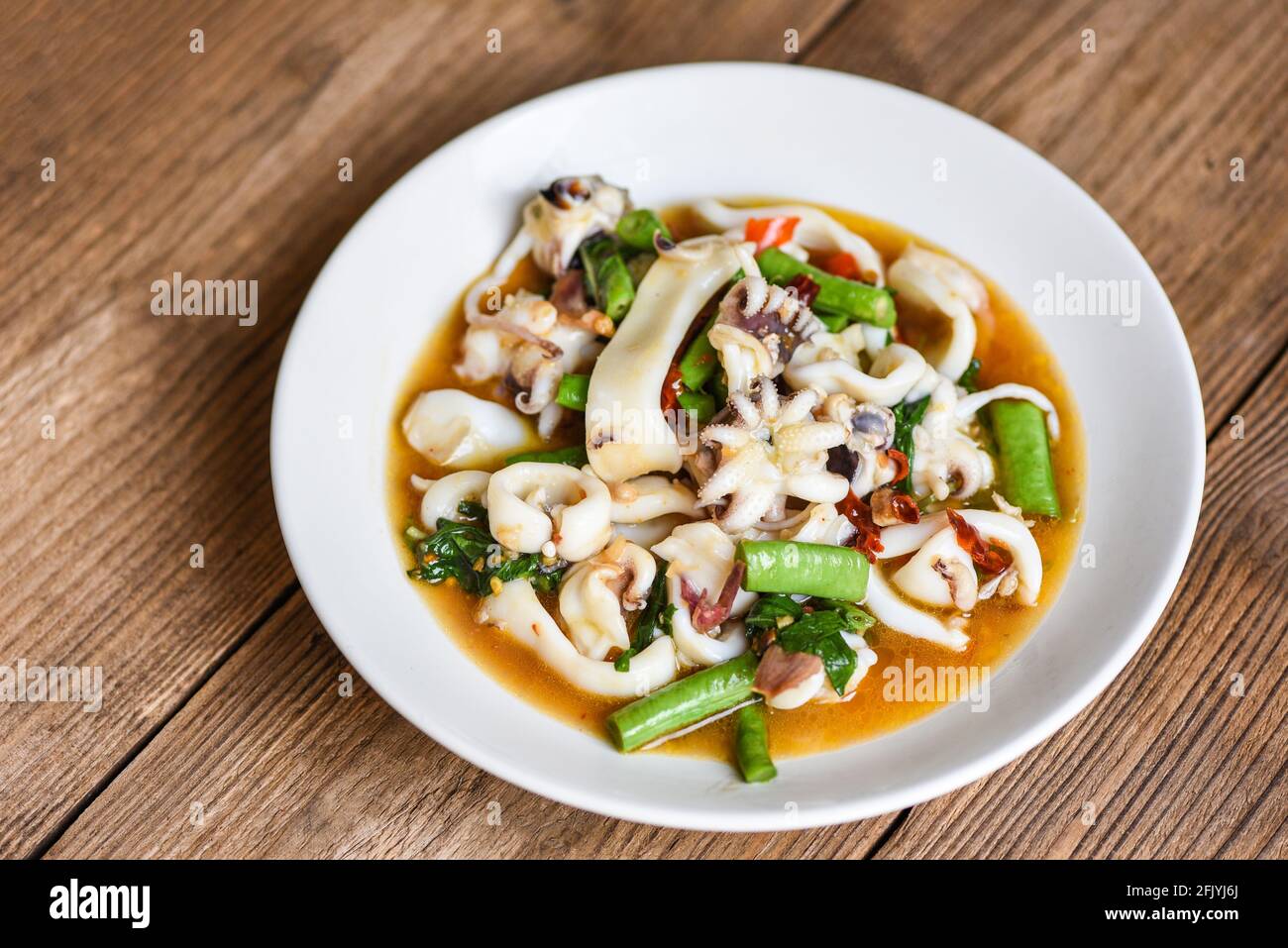 Fried squid with basil on white plate, Stir fried spicy basil leave ...