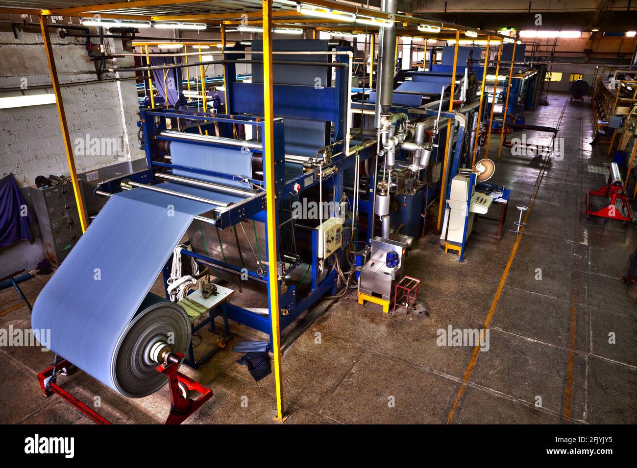 Denim getting steamed press in rolls in denim manufacturing industry ...