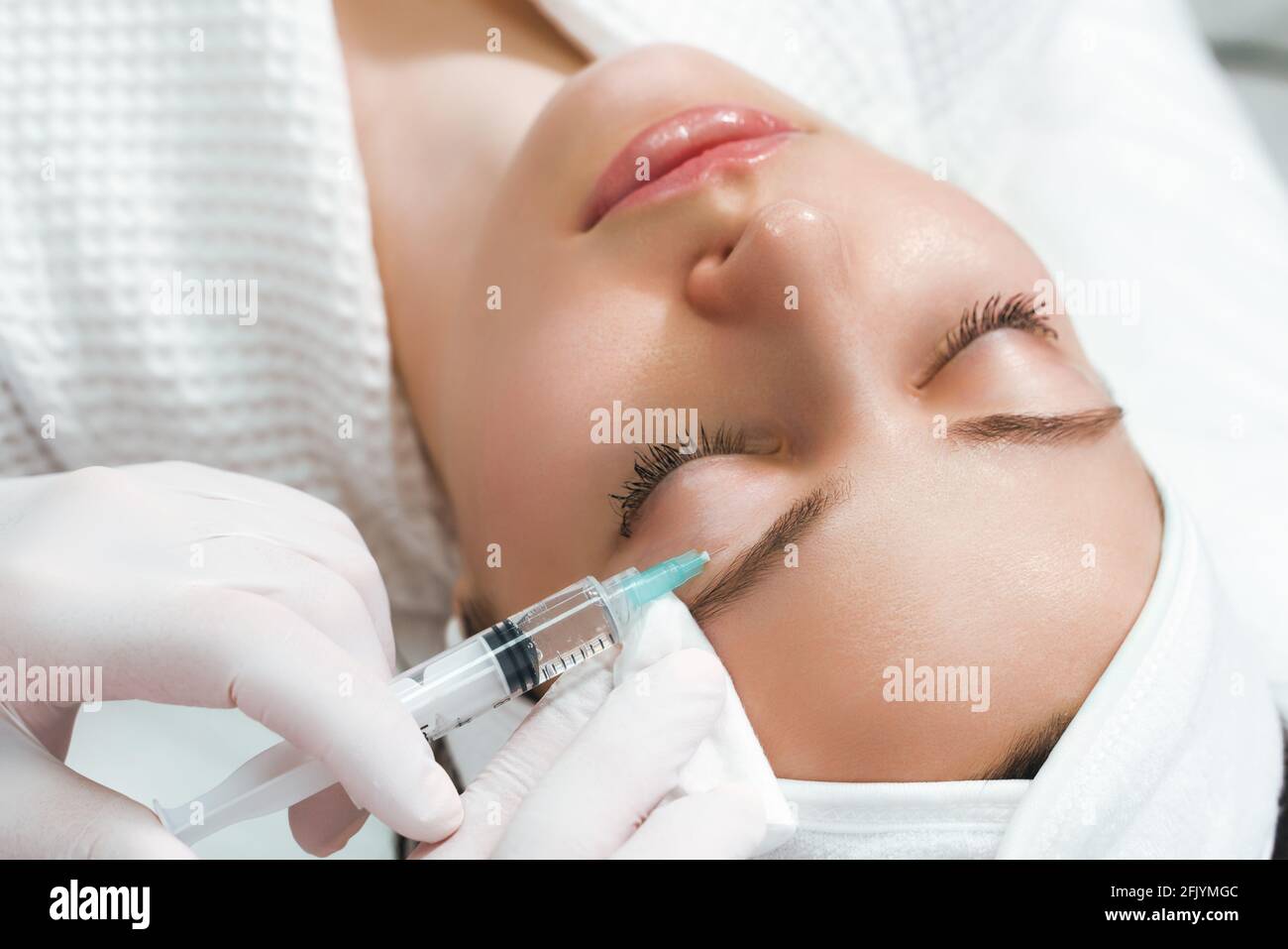 The doctor cosmetologist makes the rejuvenating facial injections ...