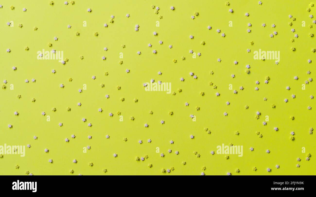 Festive frame made of colorful pastel sprinkles on a yellow background ...