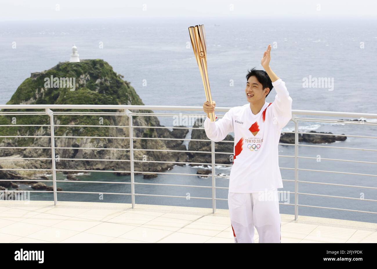 A Tokyo Olympic torch relay runner waves after arriving at an ...
