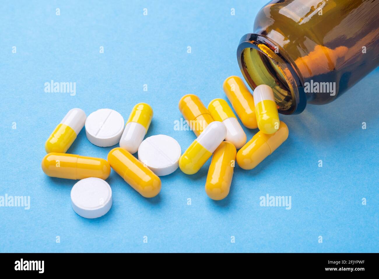 Multicolor tablets and pills capsules from glass bottle on blue ...