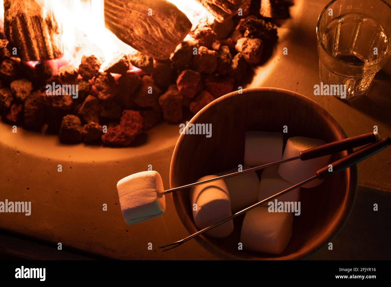 Roasting marshmallow over a gas fire while glamping Stock Photo - Alamy