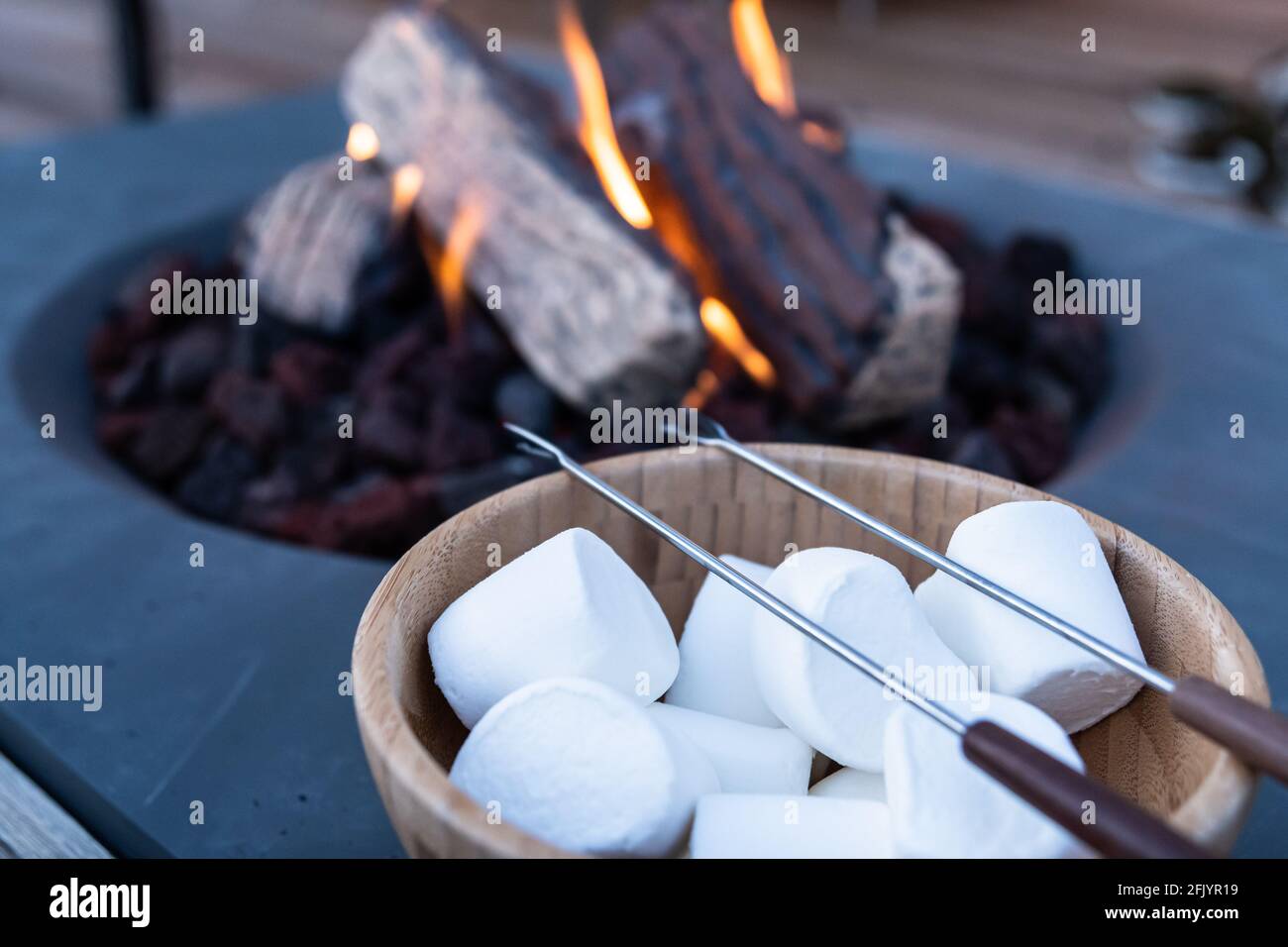 Roasting marshmallow over a gas fire while glamping Stock Photo - Alamy