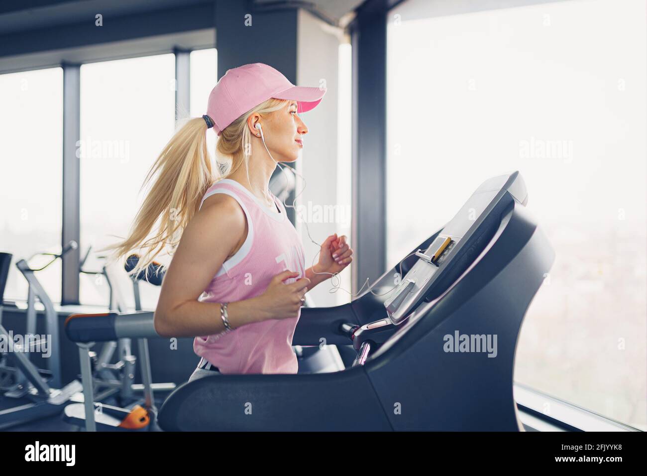 Side view of sporty blonde woman exercising on treadmill in gym Stock ...
