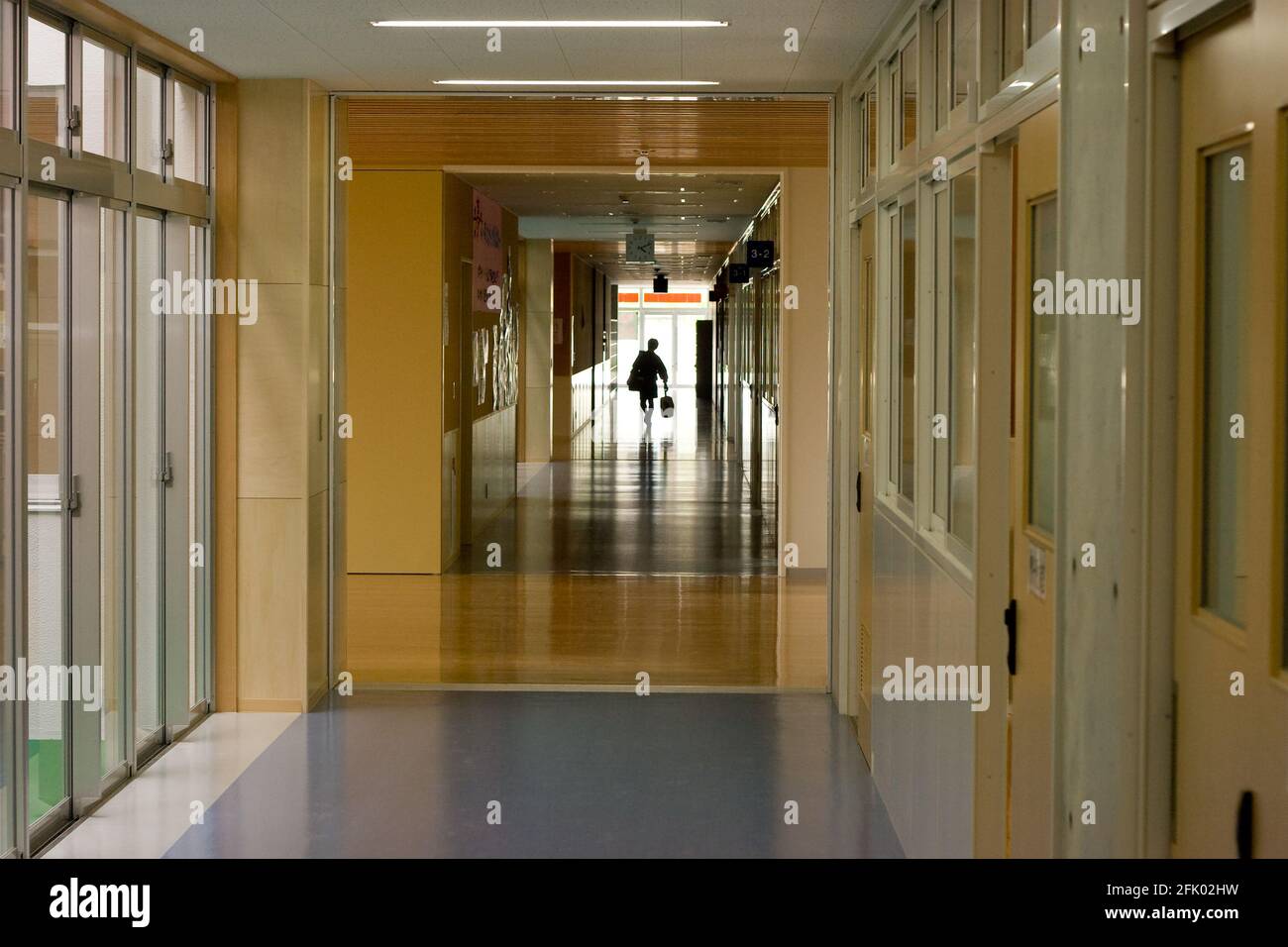 Back view of a person walking in the long empty hallway in a building ...
