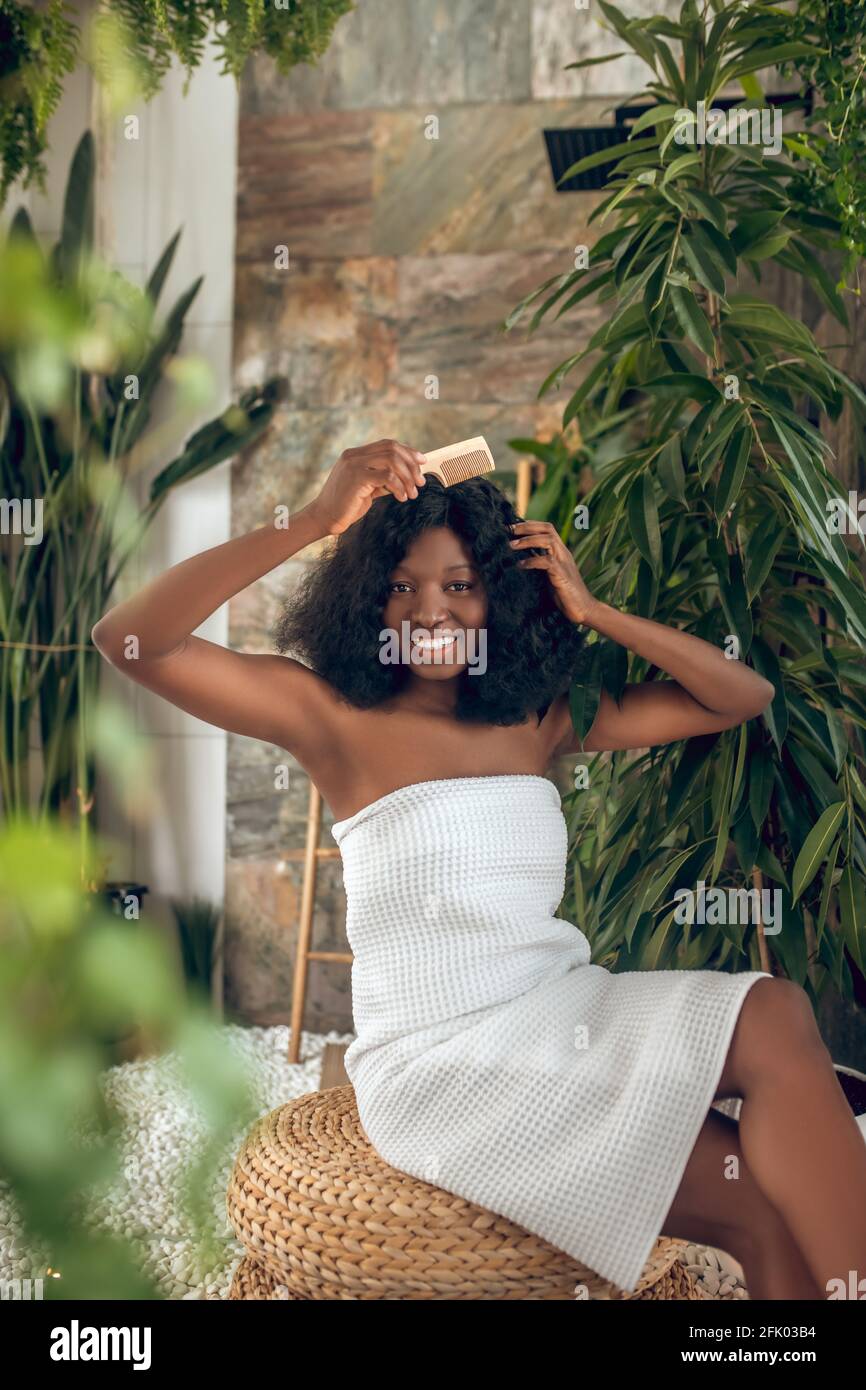 Beautiful dark-skinned woman brushing her hair and feeling comfortable ...