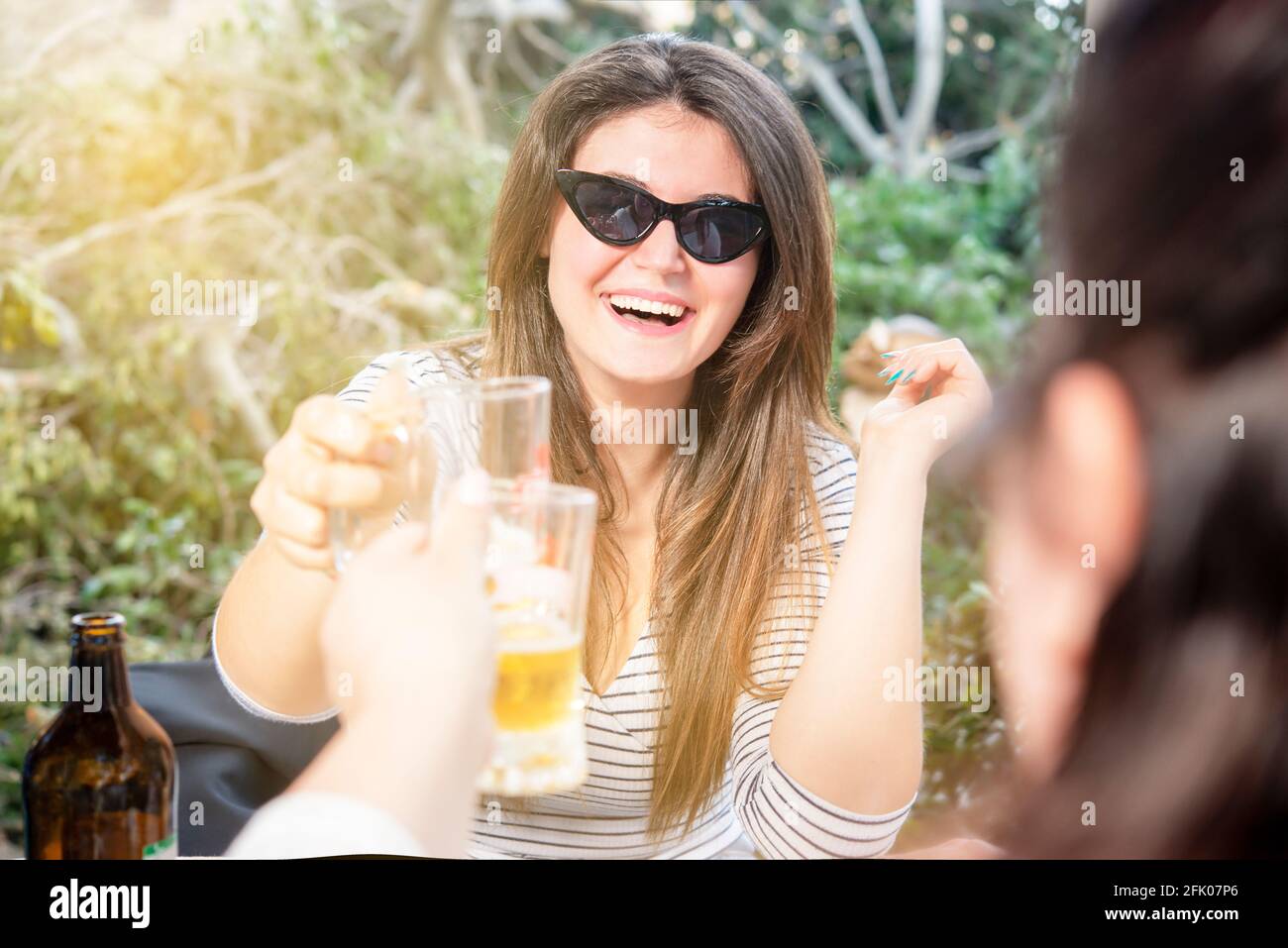 happy young woman with sunglasses smiles and toasts enjoying friends in ...