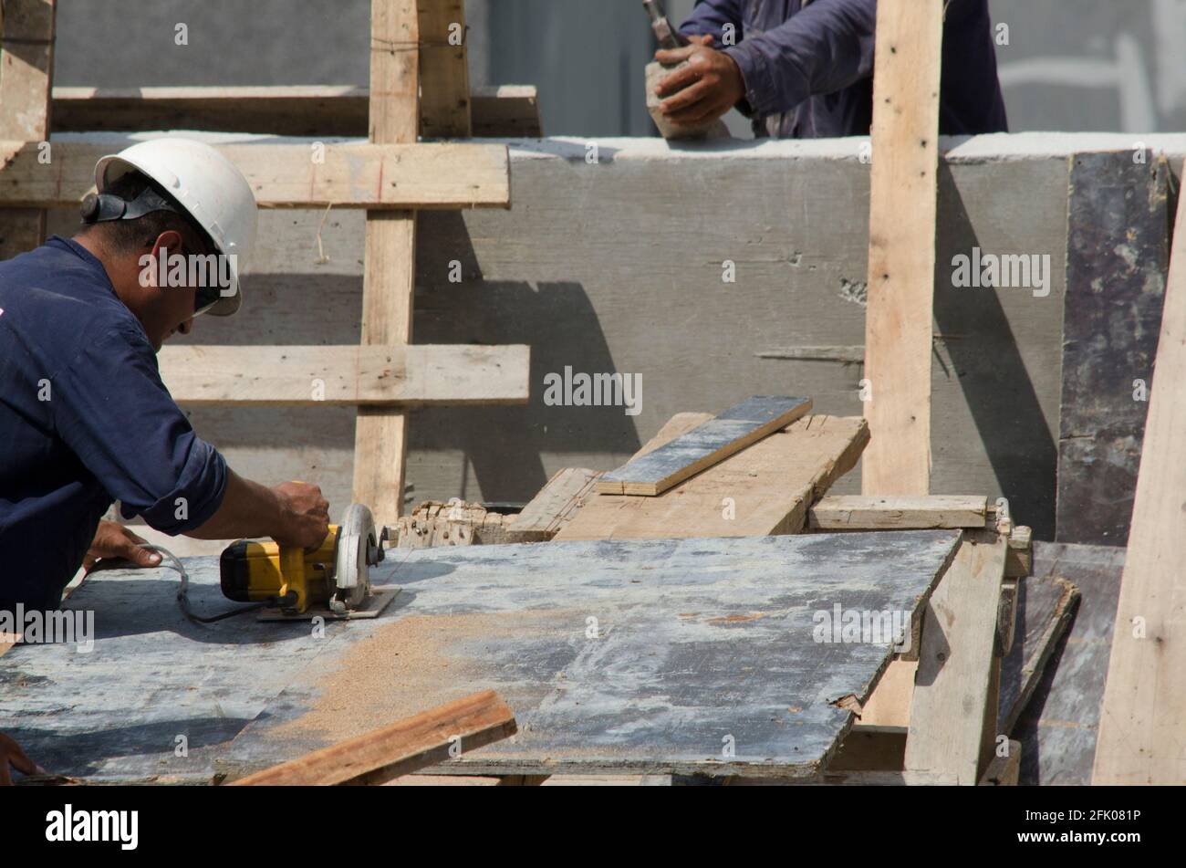 construction worker cutting with a circular saw wearing work clothes ...