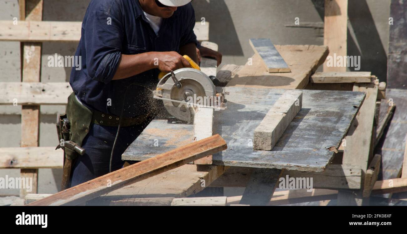 Construction worker cutting with circular saw with work clothes and ...