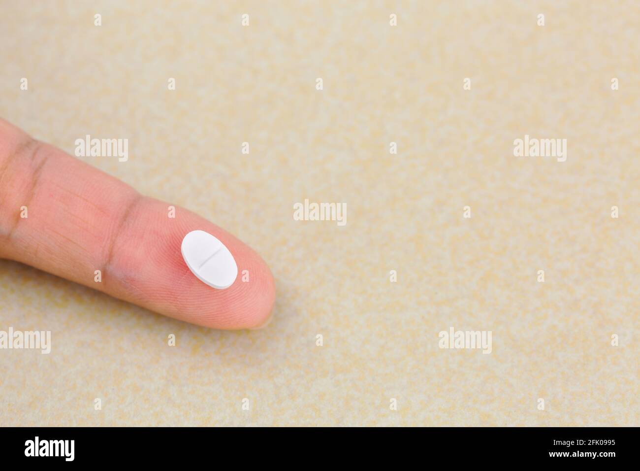 Anti anxiety white pill medicine on finger with blurred yellow ...