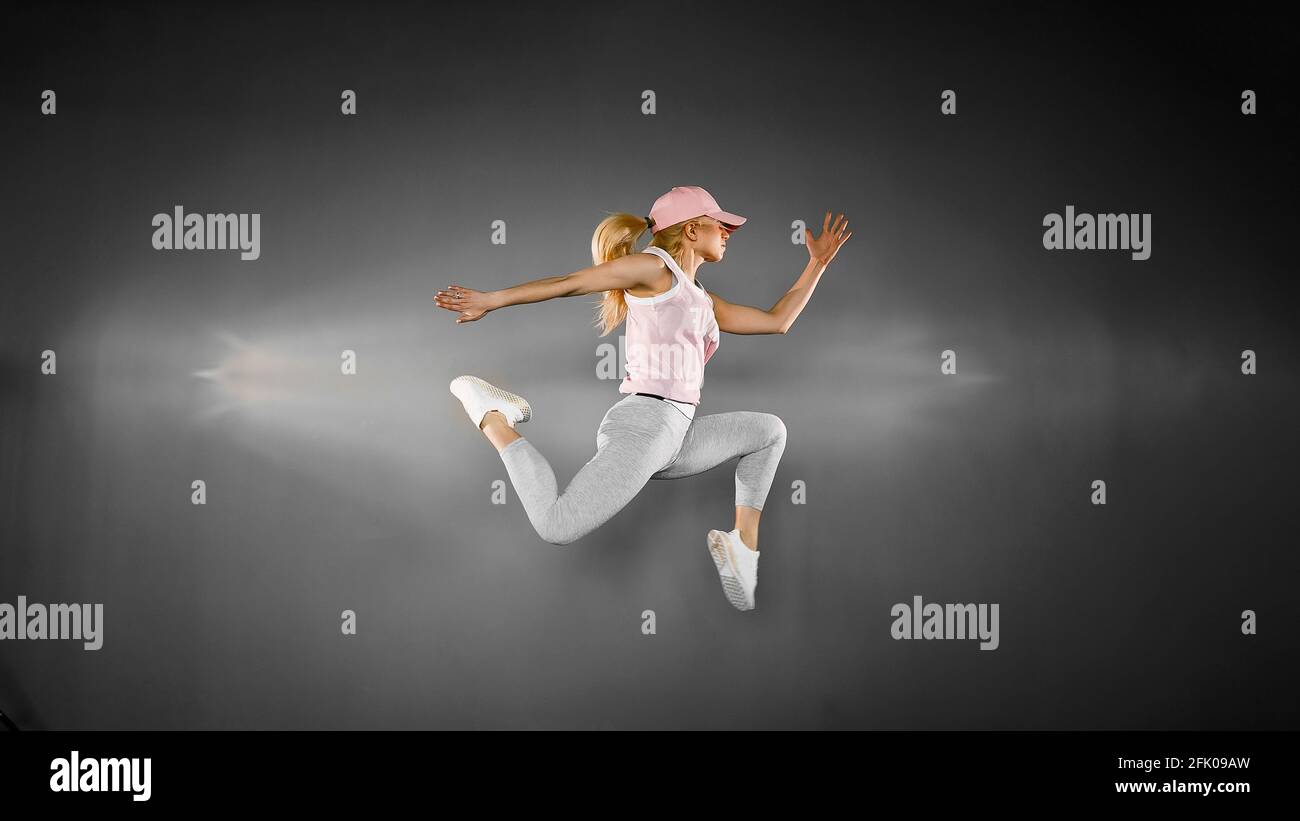 Young woman with fit body jumping and running against grey backg Stock ...