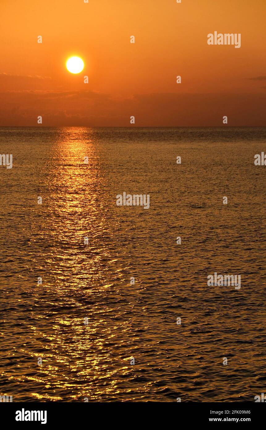Sun going down at sea with a beautiful orange and warm tone Stock Photo ...