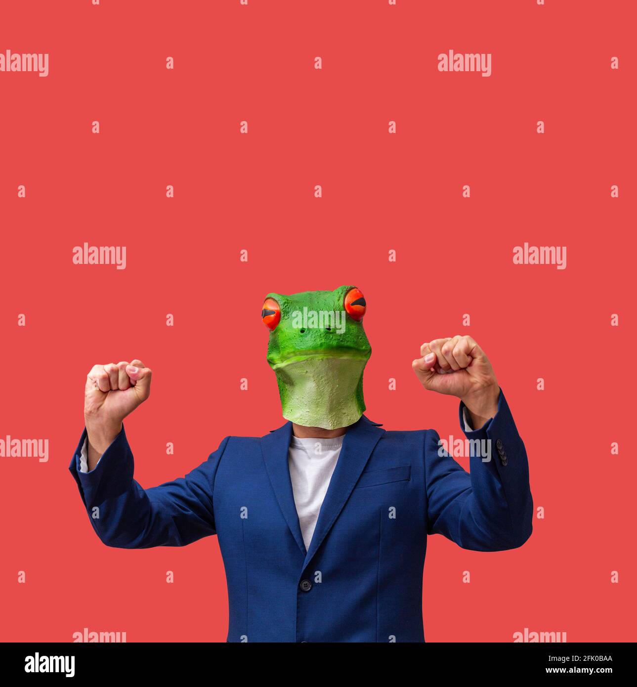 man with googly-eyed frog mask euphoric with arms in the air ...