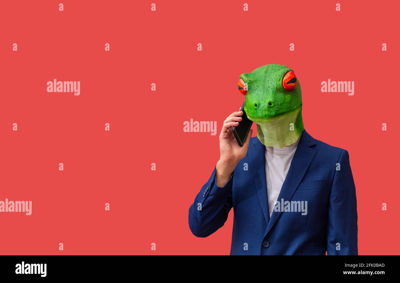 man with googly-eyed frog mask calling with smart phone on red ...