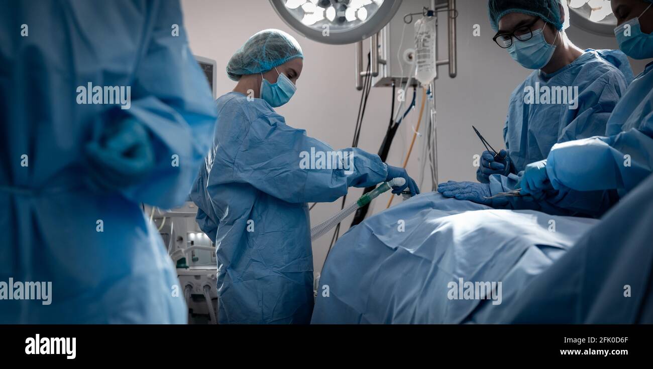 Diverse group of male and female surgeons in operating theatre wearing ...