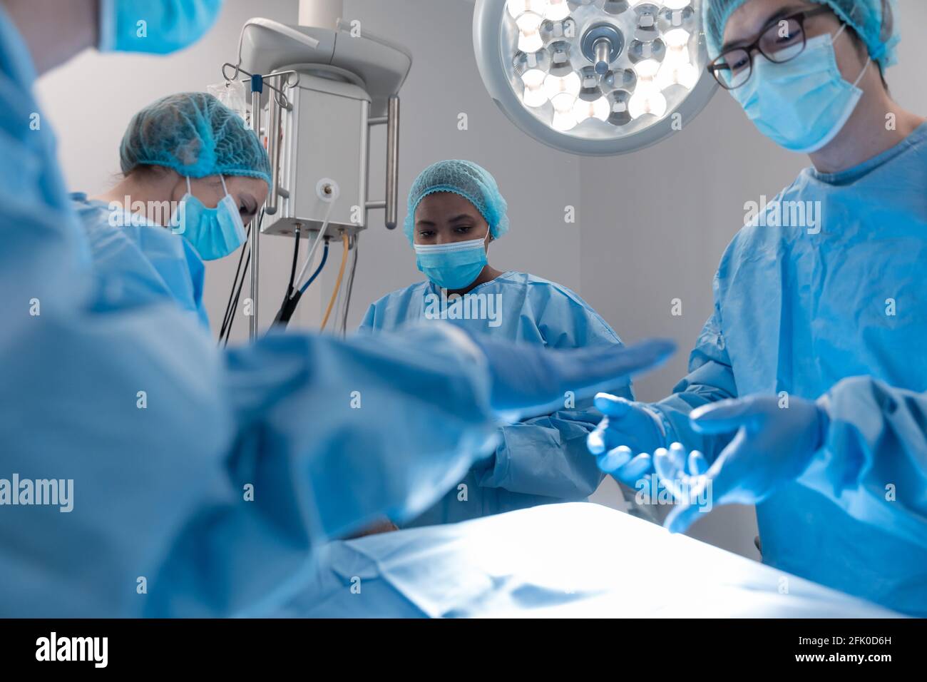 Diverse group of male and female surgeons in operating theatre wearing ...