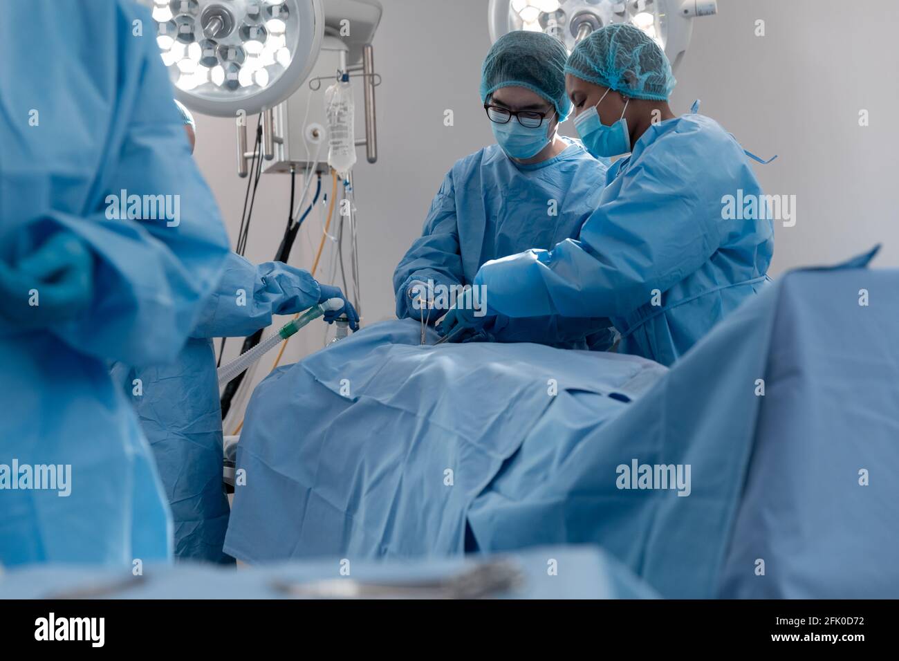 Diverse group of male and female surgeons in operating theatre wearing ...