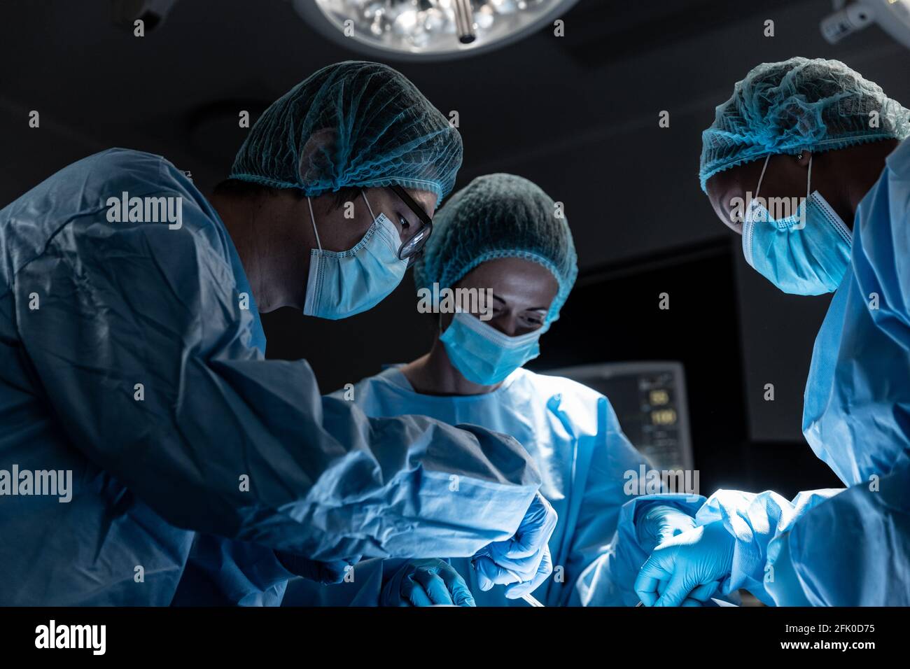 Diverse group of male and female surgeons in operating theatre wearing ...
