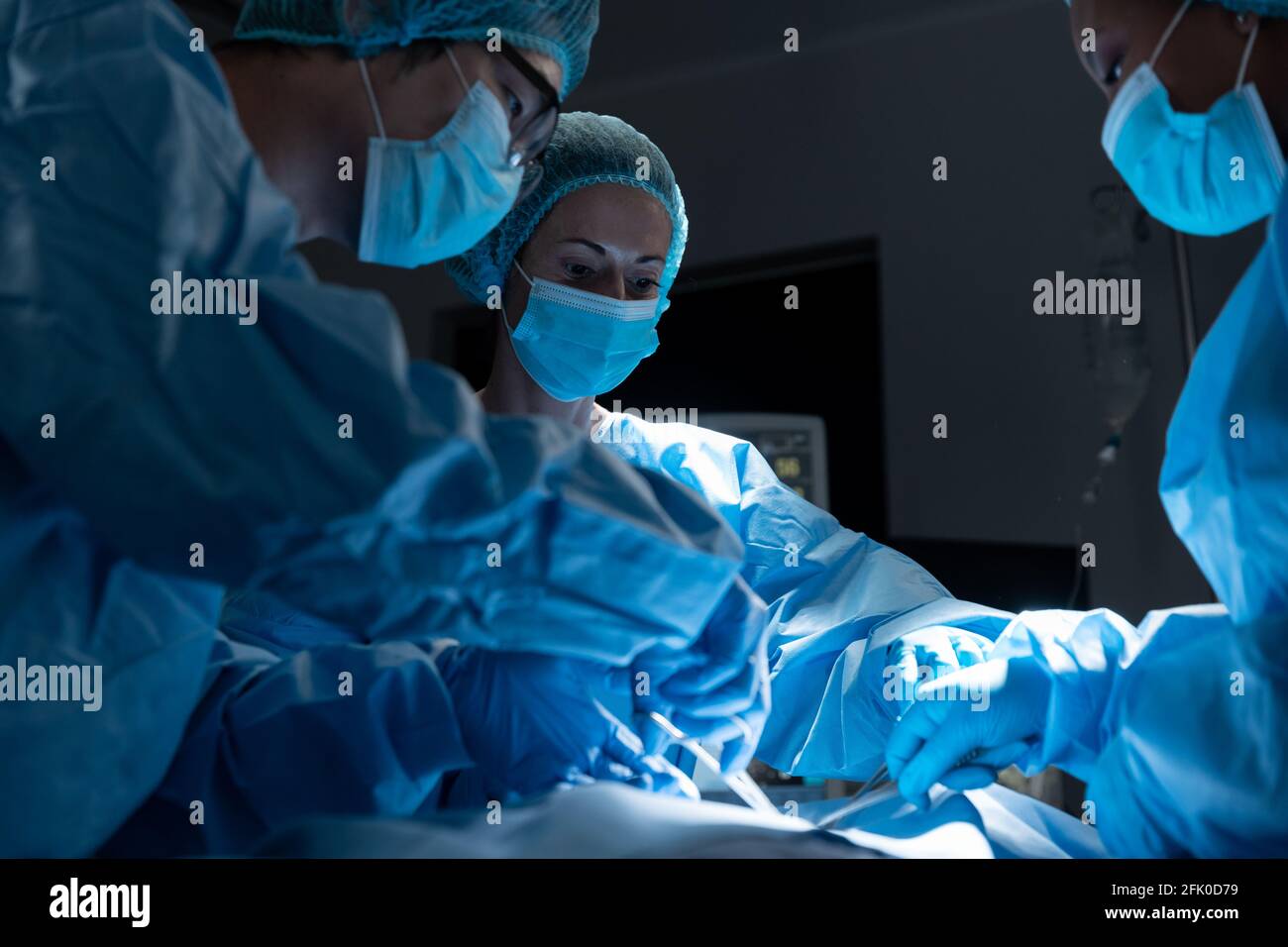 Diverse group of male and female surgeons in operating theatre wearing ...