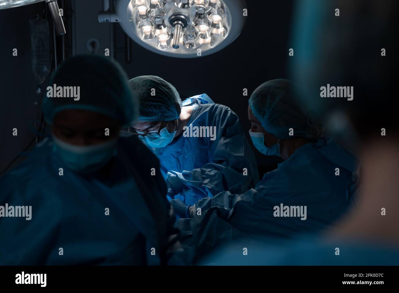 Diverse group of male and female surgeons in operating theatre wearing ...