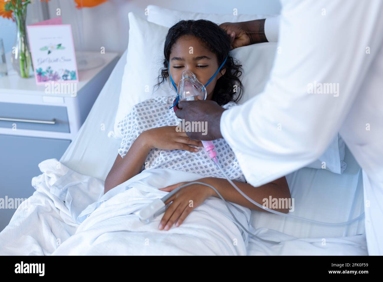 Midsection of male doctor putting oxygen mask ventilator on sick mixed ...