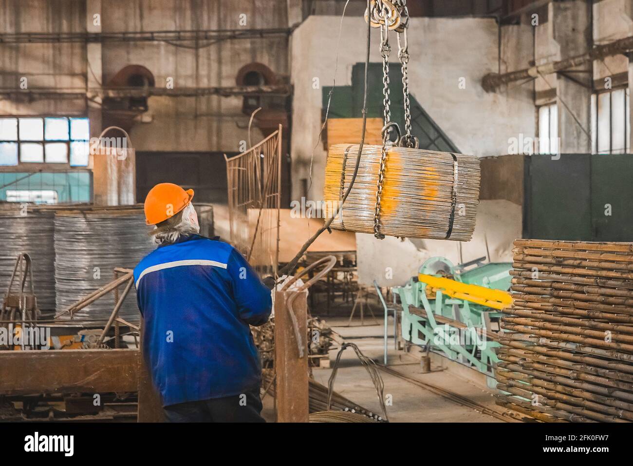 Worker in a reinforcement workshop in a helmet controls equipment for ...