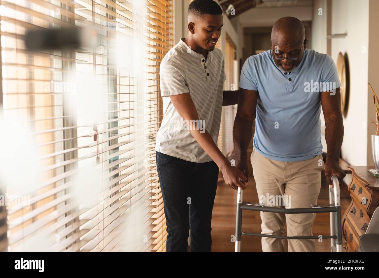 African american young man helping his father to walk with walking ...